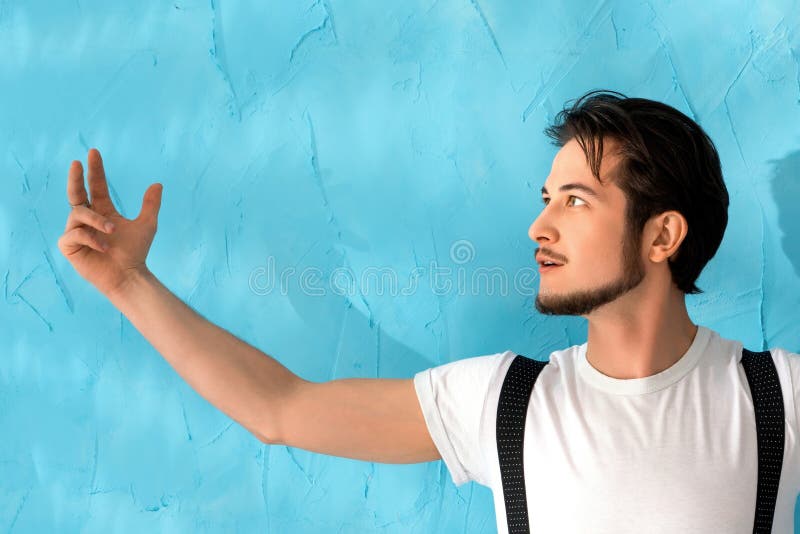 Young Man Striking a Creative Pose Against a Colorful Blue Wall Stock ...