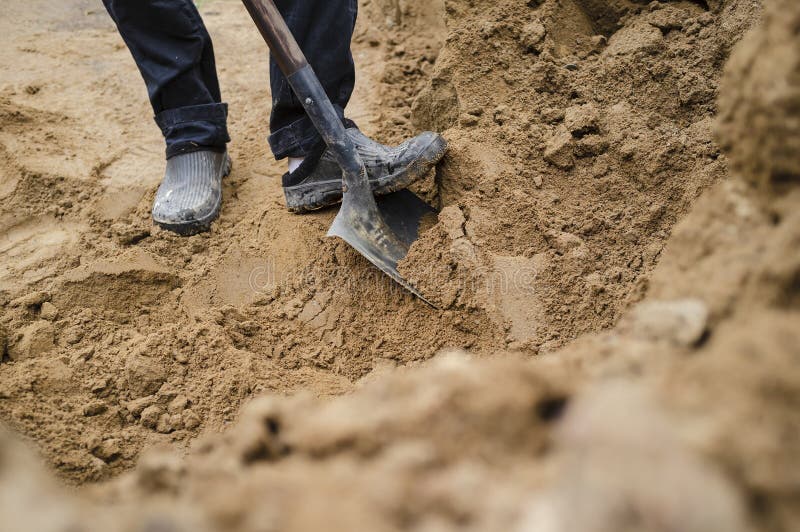 A Man Stands on a Pile of Sand, and Digging with a Shovel. Stock Image ...