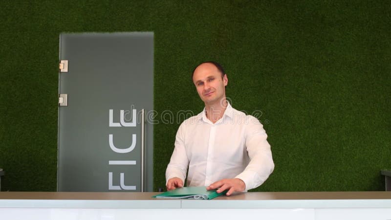 Man Stands at the Reception and Puts the Folder on Stock Footage ...