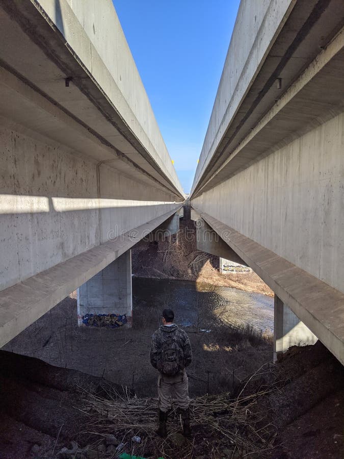 A Man Stands Under a Bridge Over a Valley with a River Stock Image ...