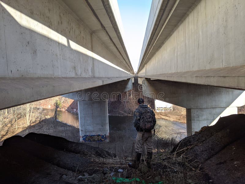 A Man Stands Under a Bridge Over a Valley with a River Stock Image ...
