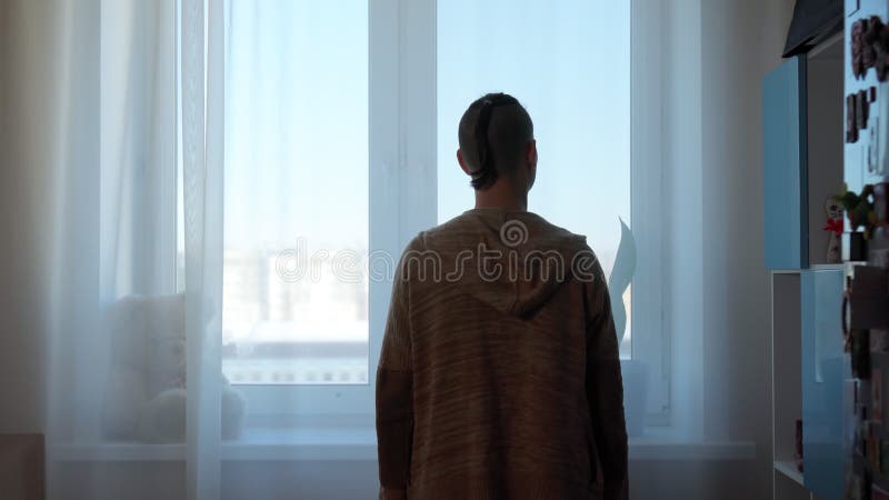Rear View of a Man Standing in Front of a Window and Looking Out at ...