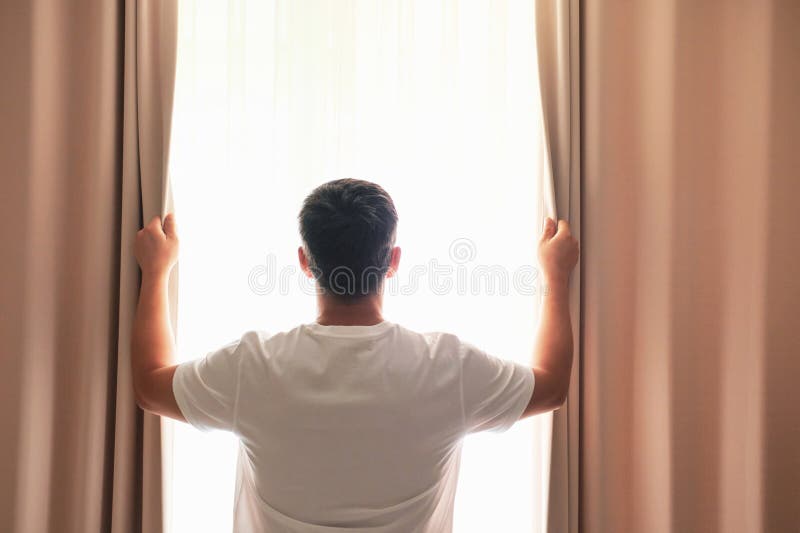 Man Stands at Window and Opens Brown Curtains Back View. Stock Image ...