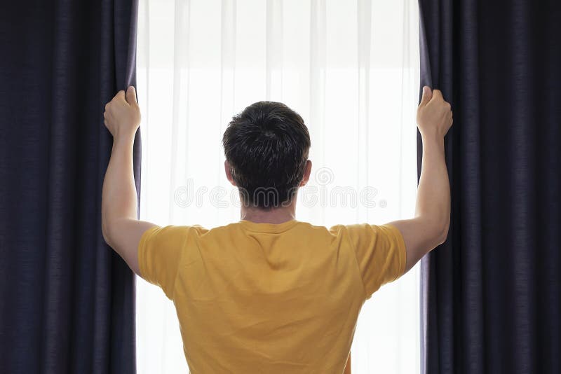 Man Stands at Window and Opens Curtains, Back View. Stock Image - Image ...