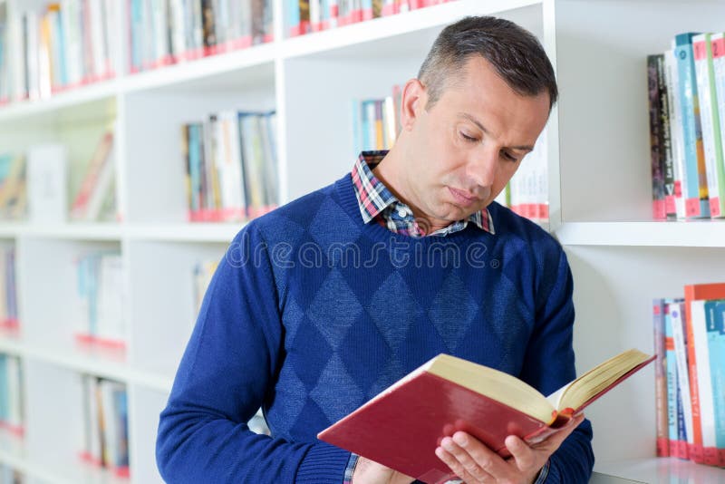 Man Stood Looking at Book in Library Stock Photo - Image of repository ...