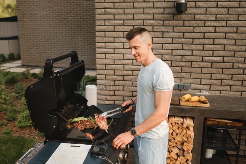 A Man on the Street is Cooking a Steak on the Grill at a Barbecue Stock ...