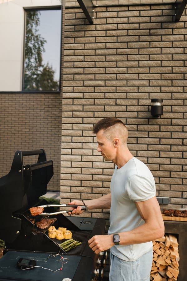 A Man on the Street is Cooking a Steak on the Grill at a Barbecue Stock ...