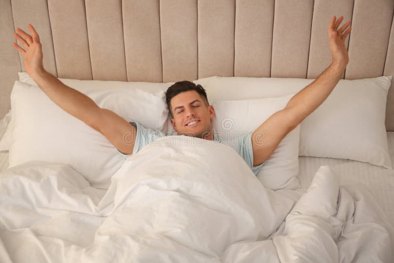 Man Stretching in Bed with Linens at Home Stock Photo - Image of cover ...