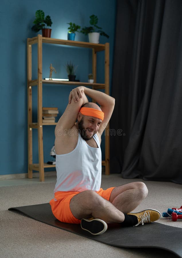 Man Stretching Triceps while Seated on Exercise Mat during Home Workout ...