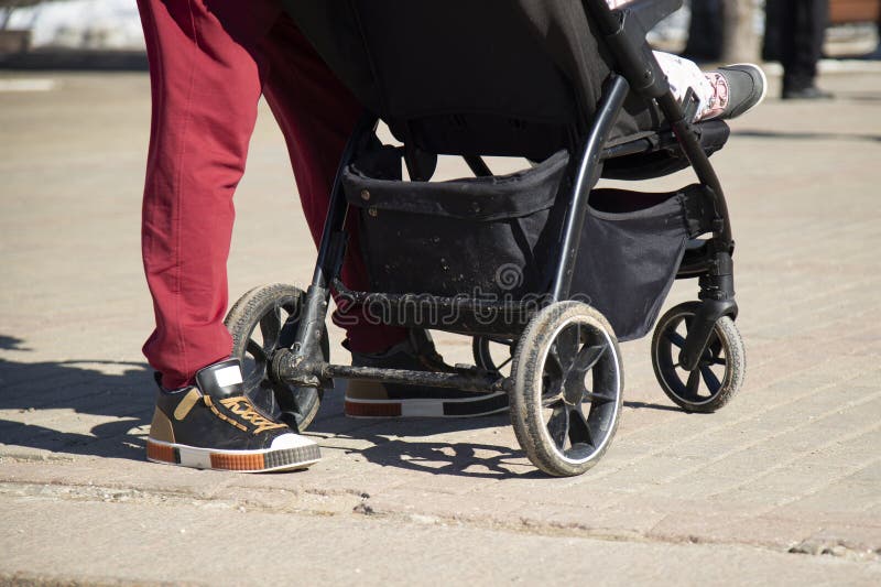 A Man with a Stroller, Where a Child is Sitting on a City Street Stock ...