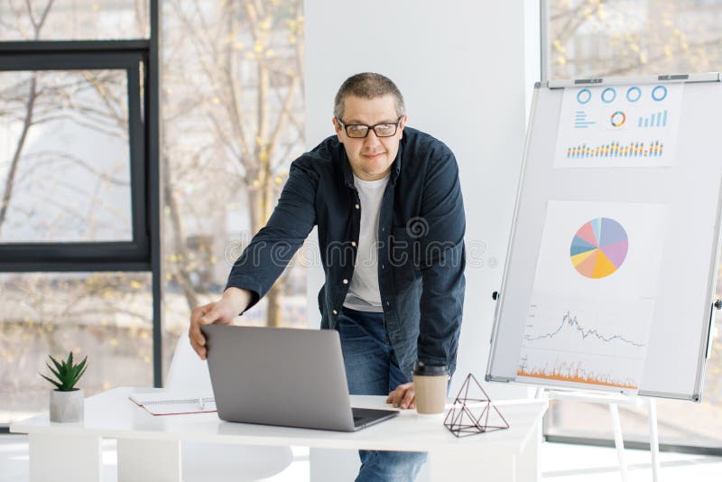 A Man, Strong Physique, Dressed in Casual Clothes Works in the Office ...