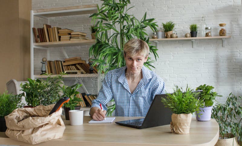 A Man Studies and Takes Notes with a Laptop Studying House Plants ...