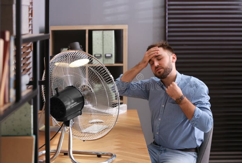 Man Suffering from Heat in Front of Fan at Workplace Stock Image ...