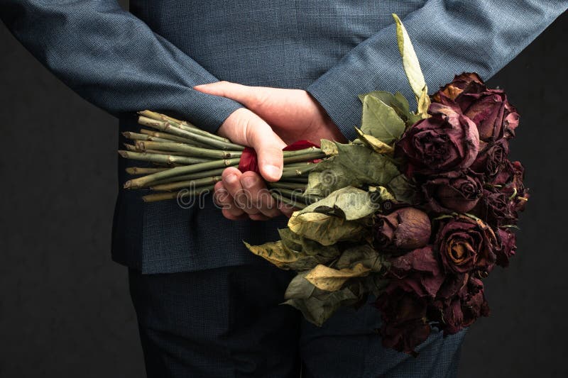 Man in Suit Holding Faded Roses Behind the Back Concept Stock Photo ...