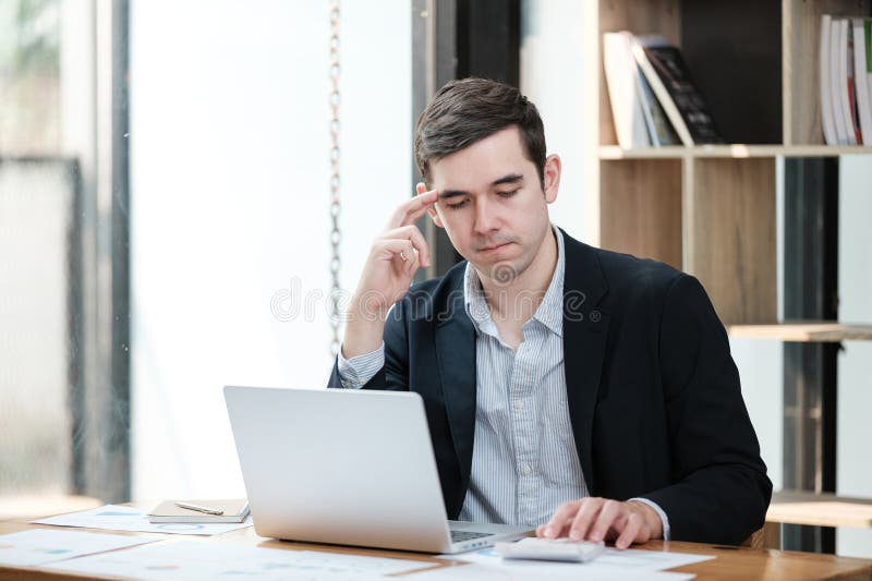 A Man in a Suit is Sitting at a Desk with a Laptop in Front of Him ...