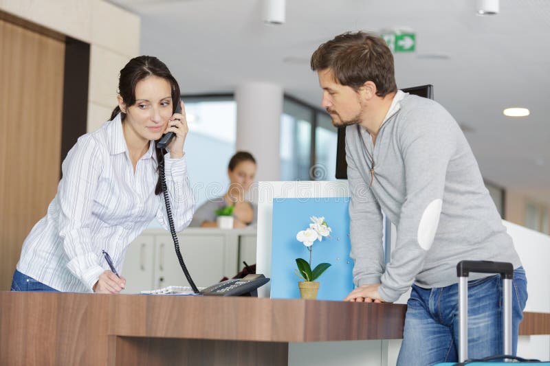 Man with Suitcase Checking in at Reception Desk Stock Image - Image of ...