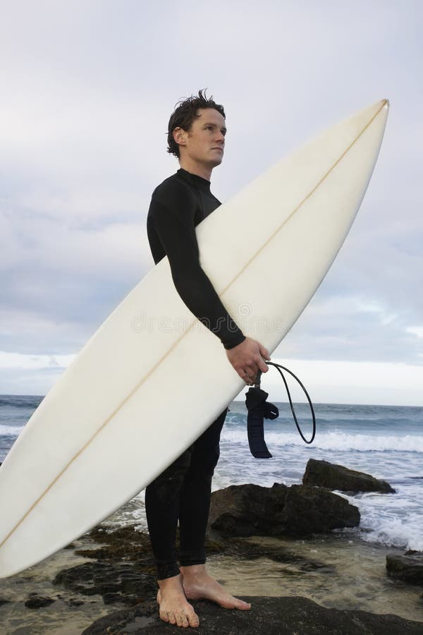 Man with Surfboard Standing on Rock at Beach Stock Image - Image of ...