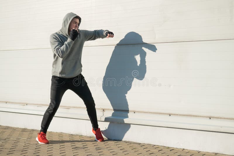 A Man in a Hoody Trains Boxing Against a Gray Wall. Stock Photo - Image ...