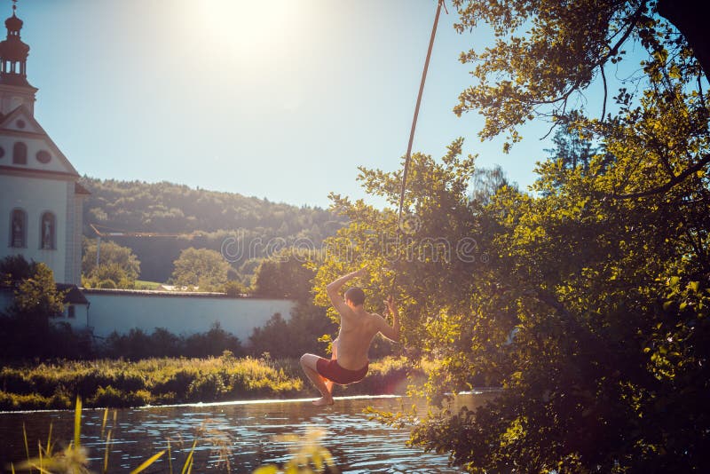 Man Swinging on a Rope into the Water of a River Stock Image - Image of ...