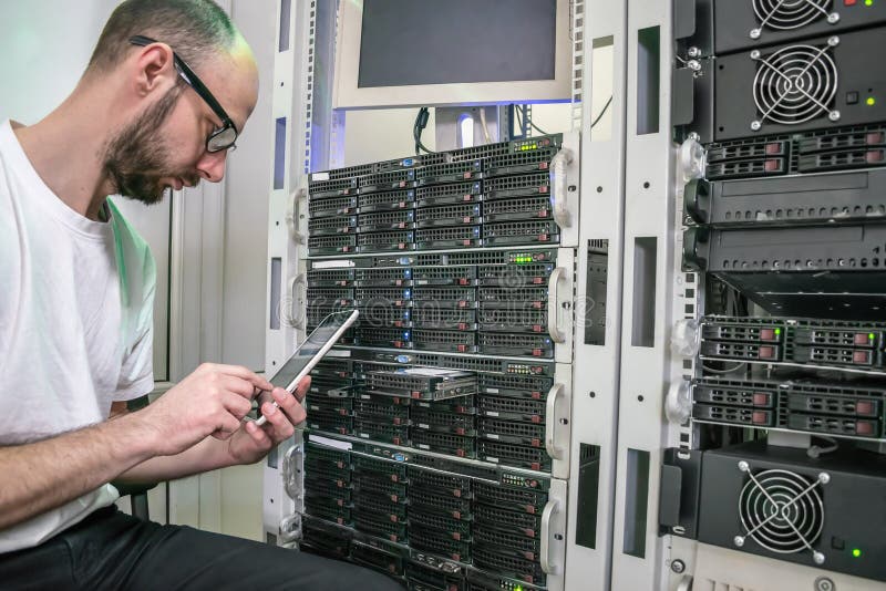A Man with a Tablet Works in a Server Room. Replacing One of the Many ...
