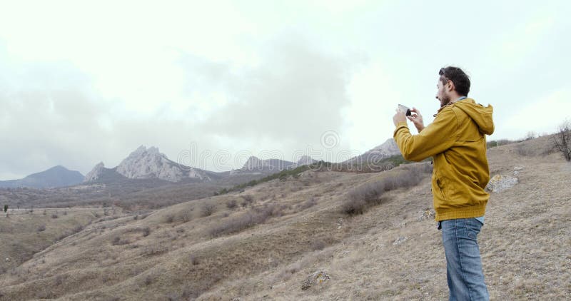 Man Take a Shots on Mobile, while Standing on Background of Mountains ...