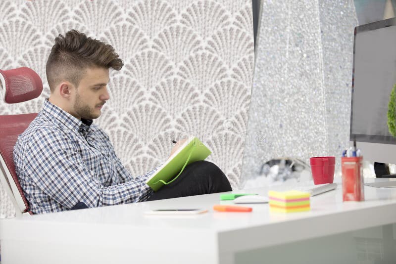 Man Taking Notes Down from His New Laptop Computer at Work in the ...