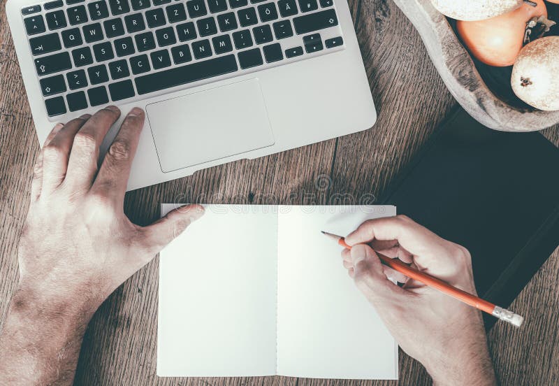 Man Taking Notes on Note Pad while Working on Laptop Computer Stock ...