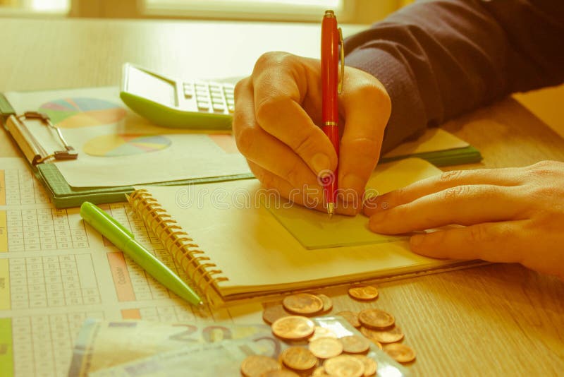 Man is Taking Notes of Saving Money in a Notebook, with a Money Jar and ...