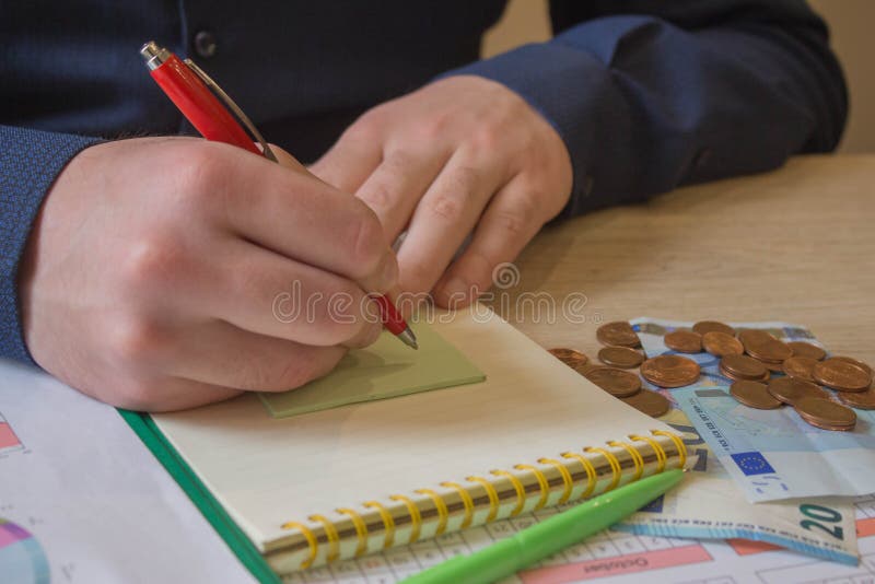 Man is Taking Notes of Saving Money in a Notebook, with a Money Jar and ...