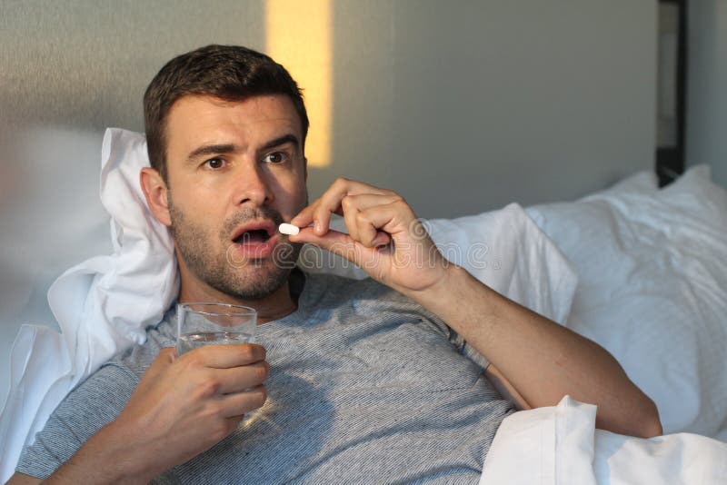 Man taking a pill in bed stock photo. Image of dependant - 120414150