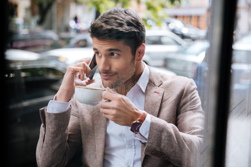 Man Talking on Mobile Phone and Drinking Coffee in Cafe Stock Photo ...