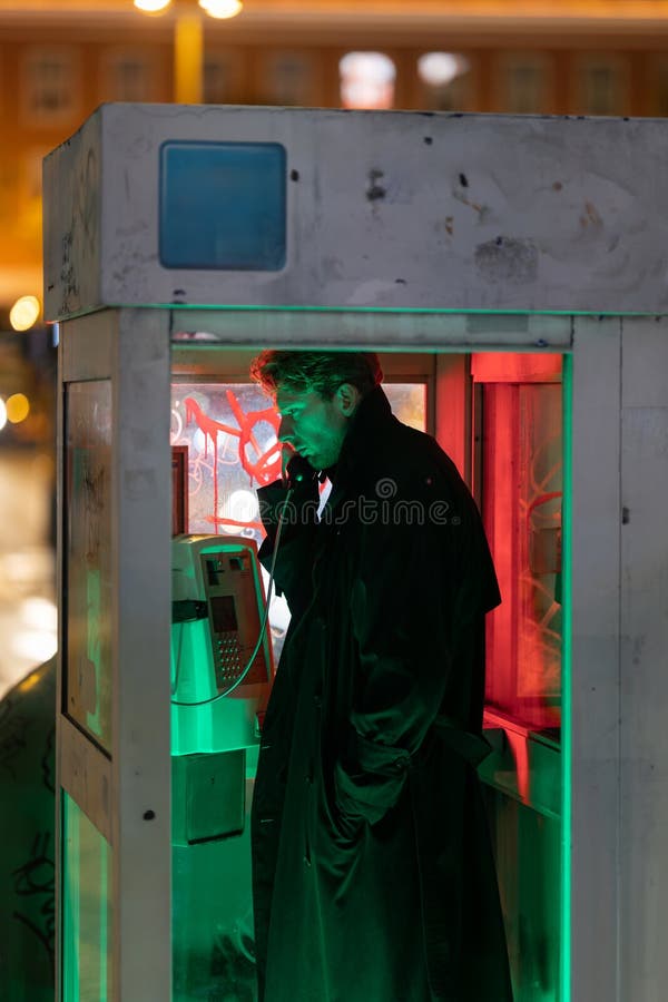 A Man is Talking on a Phone in a Booth Stock Photo - Image of night ...