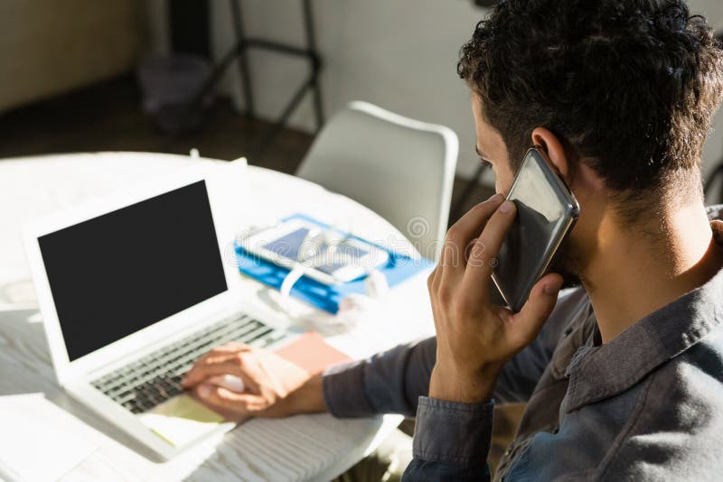 Man Talking on Phone while Using Laptop in Office Stock Photo - Image ...