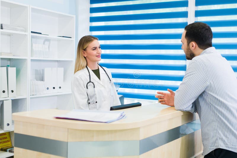 Man Talking To Female Receptionist at Hospital Stock Image - Image of ...
