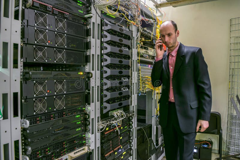 The Man is Talking To the Phone in the Server Room. Specialist in the ...