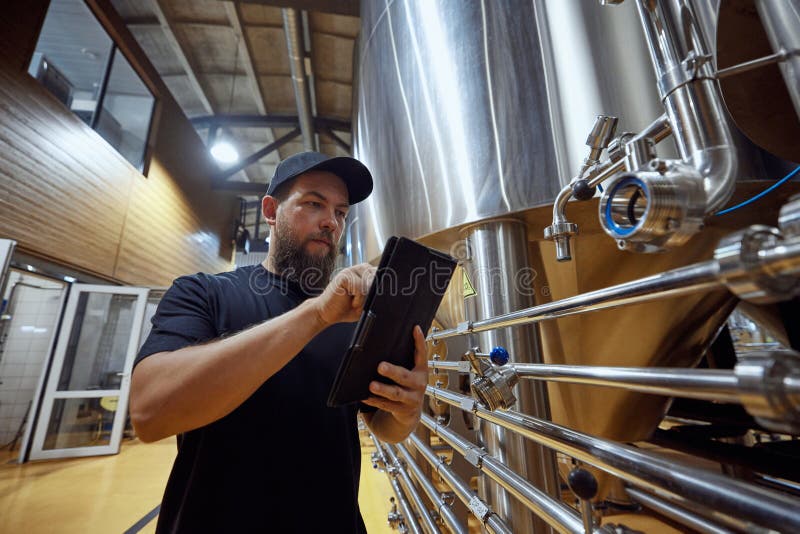 Man, Technologist with Tablet in Hand Checking the Brewing System ...