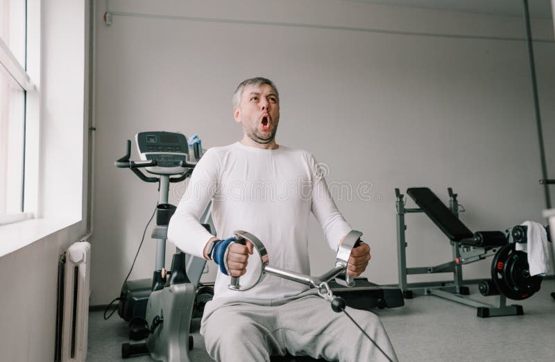 A Man with a Tense Face Performs a Deadlift on a Gym Simulator. Taking ...