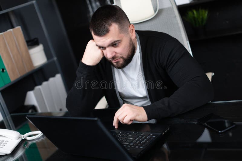 Portrait of Young Man Propping Up His Head with His Fist with Laptop in ...