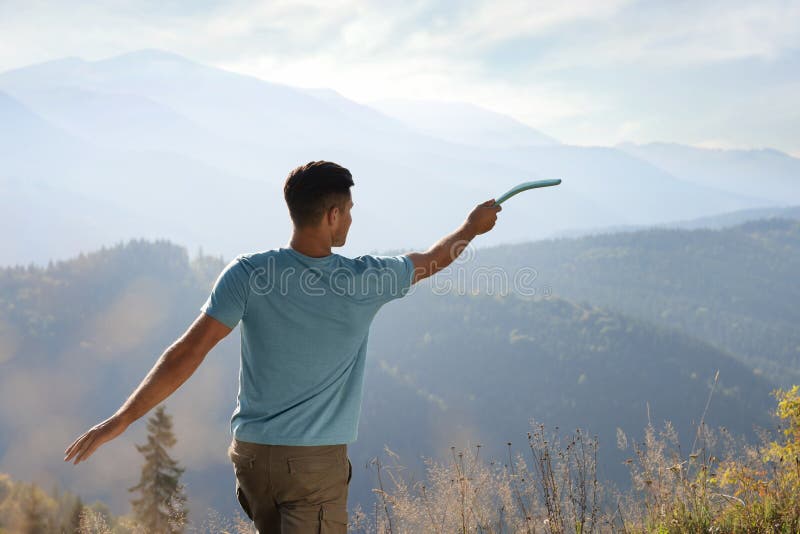 Man Throwing Boomerang in Mountains on Sunny Day, Back View Stock Photo ...