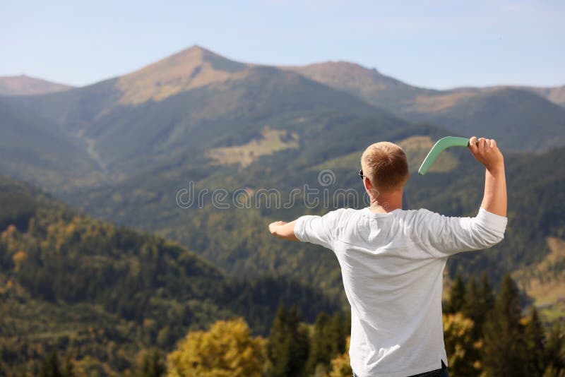 Man Throwing Boomerang in Mountains on Sunny Day, Back View. Space for ...
