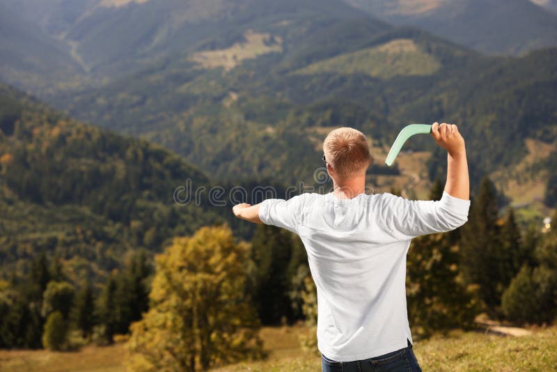 Man Throwing Boomerang in Mountains on Sunny Day, Back View. Space for ...