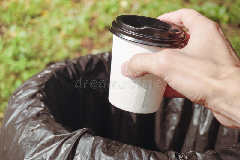 Man Throwing Coffee Cup into Bin Outdoors. a Hand Throws a Paper Cup ...