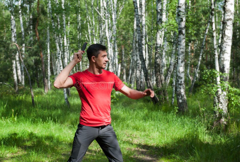 A Man Throws a Knife at a Target in the Summer Forest, Side View ...