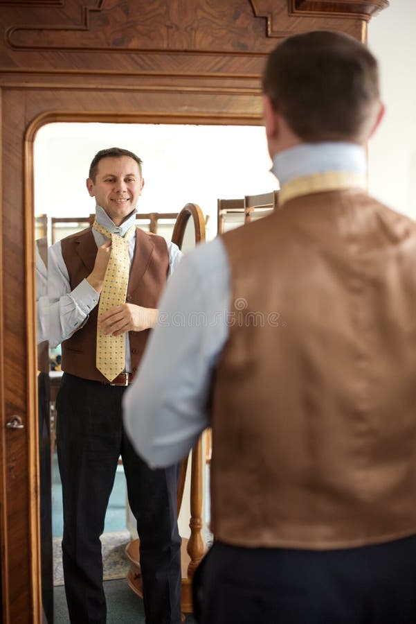 Man Tieing Tie in Front of Mirror Stock Photo - Image of mirror ...