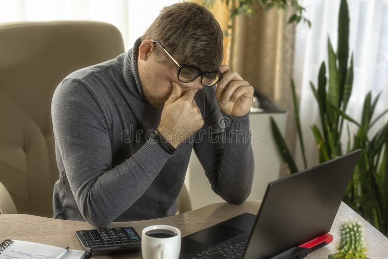 A Man Tired of Working at a Computer Rubs His Eyes. Work at Home or in ...