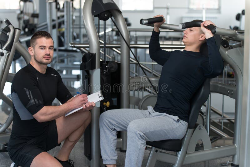 Man Train Shoulders on Machine with Personal Trainer Stock Image ...