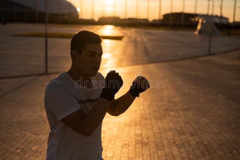A Man Trains in Boxing at the Stadium at Sunset. Athlete Silhouette ...
