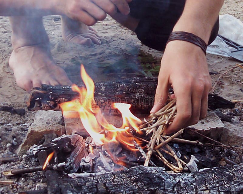 A Man Tries To Light a Fire and Throws Straw into the Fire Stock Photo ...