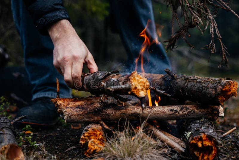 A Man Tries To Light a Fire and Throws Dry Straw into the Fire Stock ...