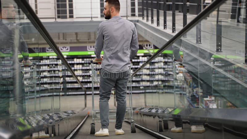A Man with a Trolley on Escalator in a Hardware Store, Back View Stock ...